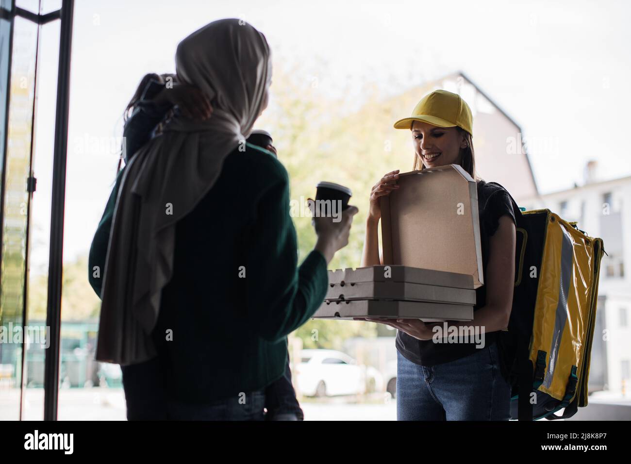Young woman delivery pizza to beautiful muslim girl customer with a ...