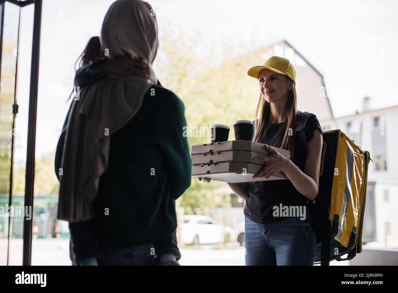 Young woman delivery pizza to beautiful muslim girl customer with a ...