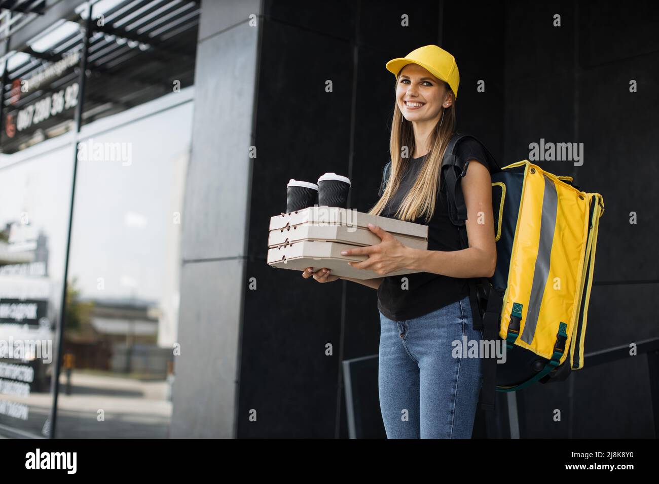 Caucasian courier delivering boxes with pizza and hot coffee. Young ...