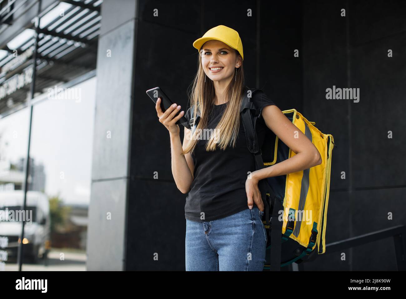 Courier woman with mobile phone looking for deliver address of food ...
