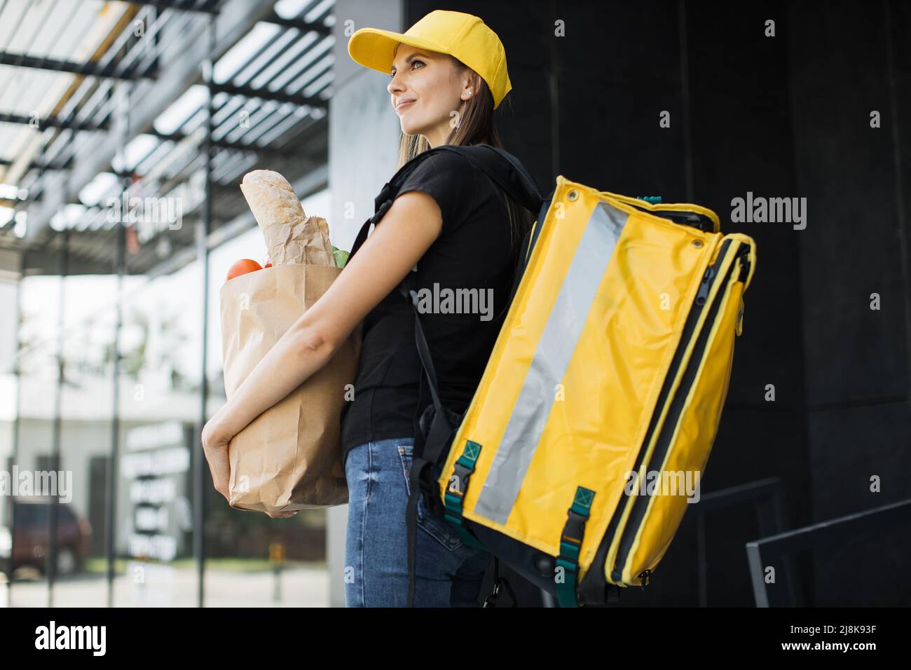 Delivery concept. Caucasian courier standing with a package with fresh ...