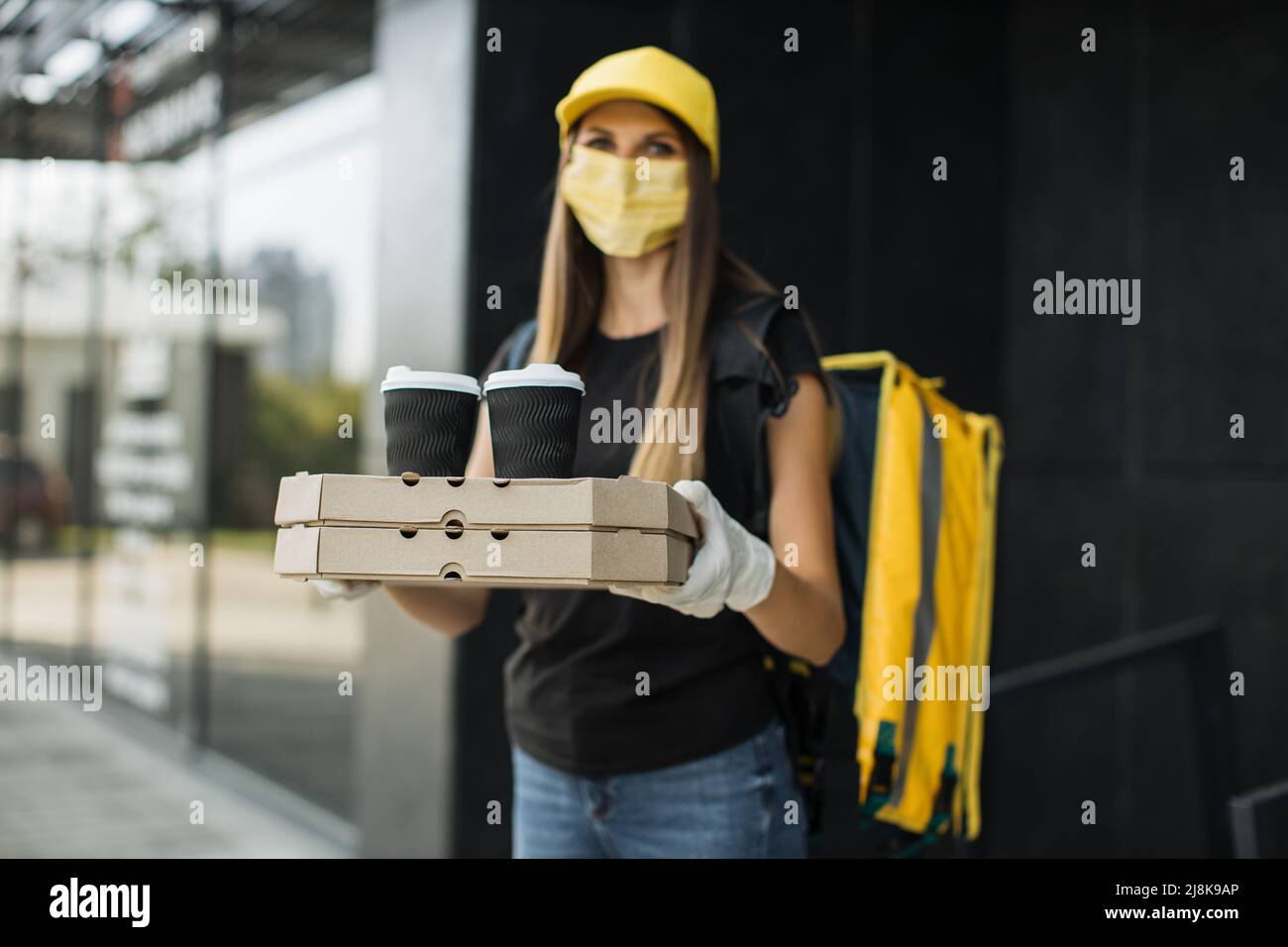Portrait of delivery woman with yellow cap in face mask and thermal ...