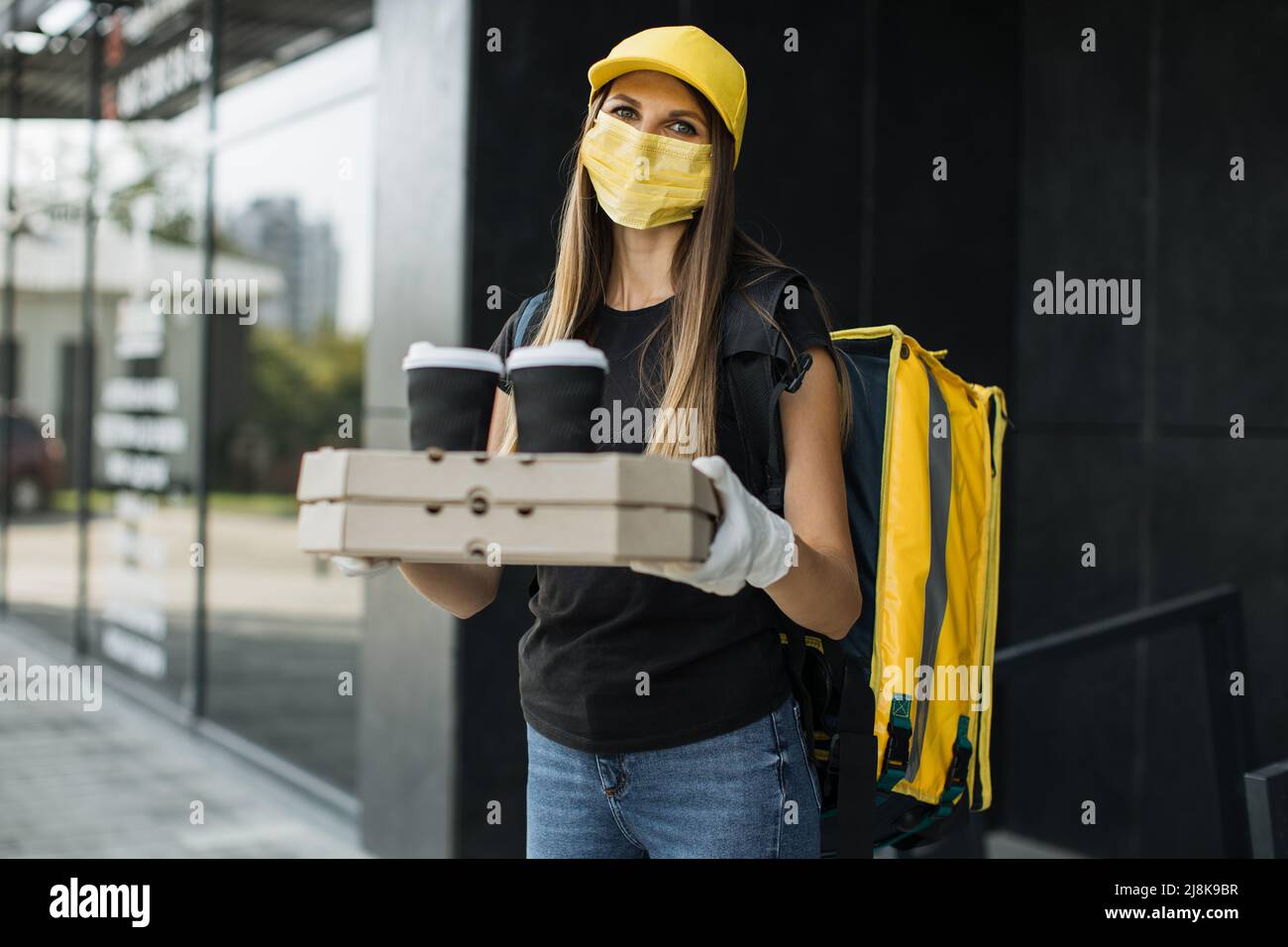 Portrait of delivery woman with yellow cap in face mask and thermal ...
