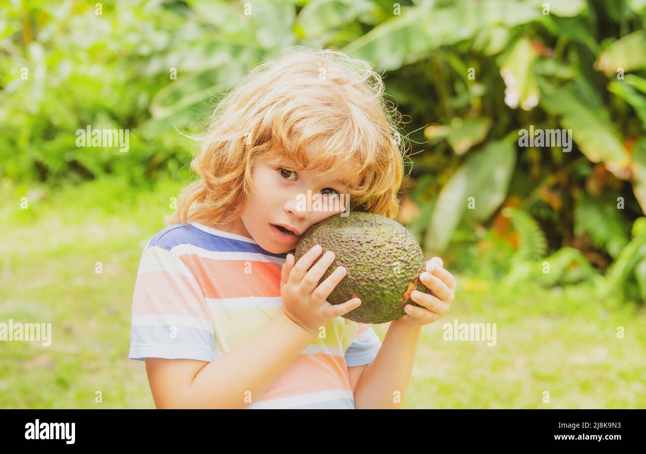 Little sweet child boy holding green avocado. Healthy food for children ...