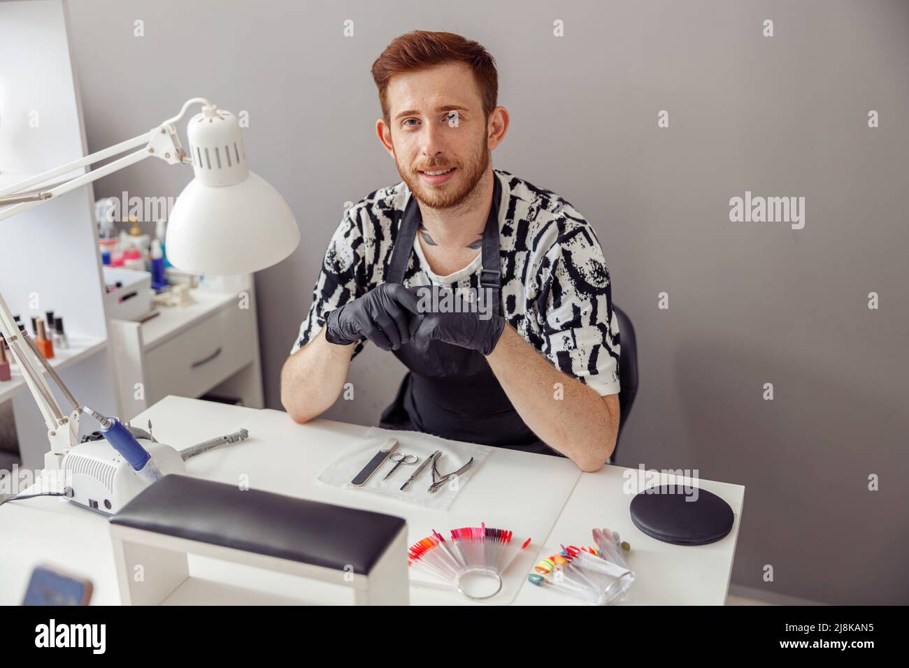 Professional nail master sitting at working place in salon Stock Photo ...