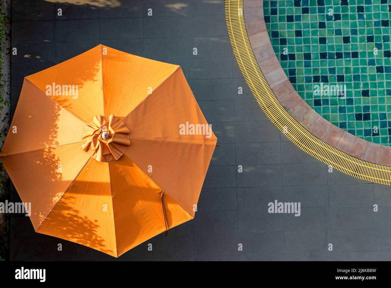 An open parasol by the swimming pool at sunset Stock Photo - Alamy