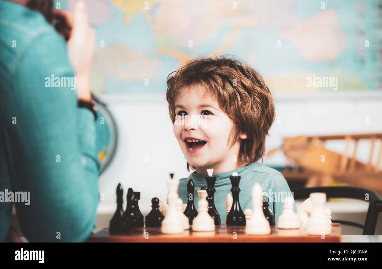 Child chess school. Cheerful smiling little boy sitting at the table ...