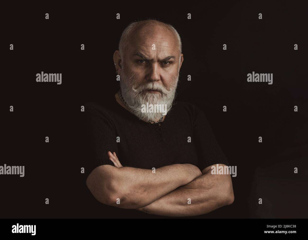 Serious Senior Man looking at camera isolated on black. Closeup low key ...