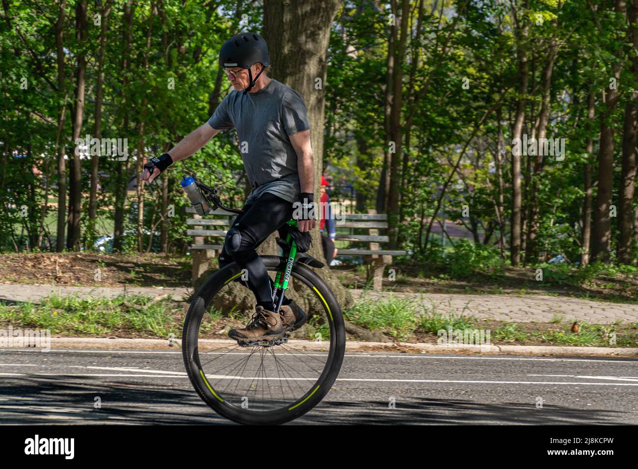A man with a helmet on a unicycle is riding in the park. Spring 2022 ...