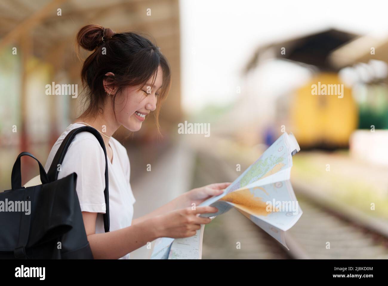 Young traveler woman looking on maps planning trip at train station ...