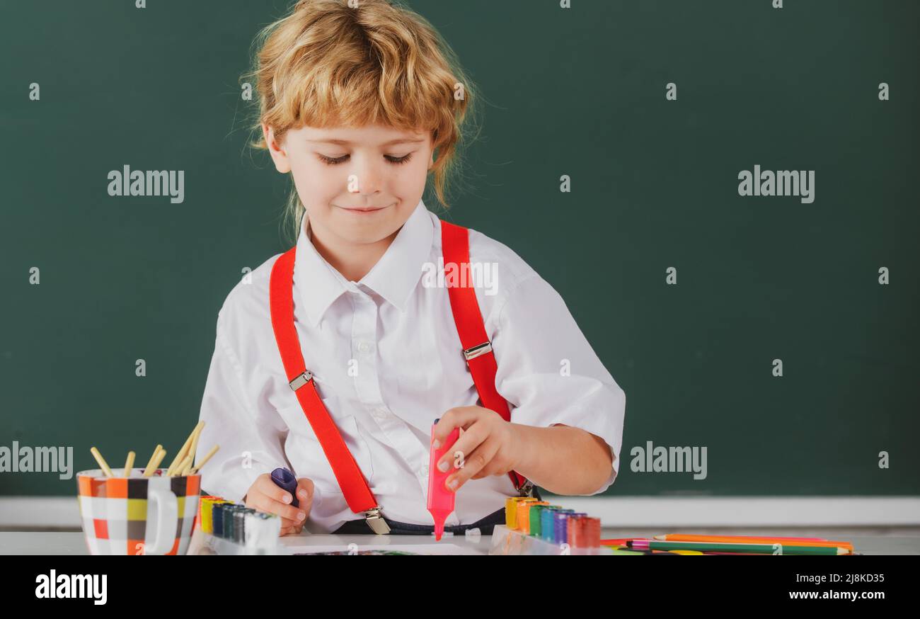 Portrait school kid boy doing art homework, holding pencil, writing ...