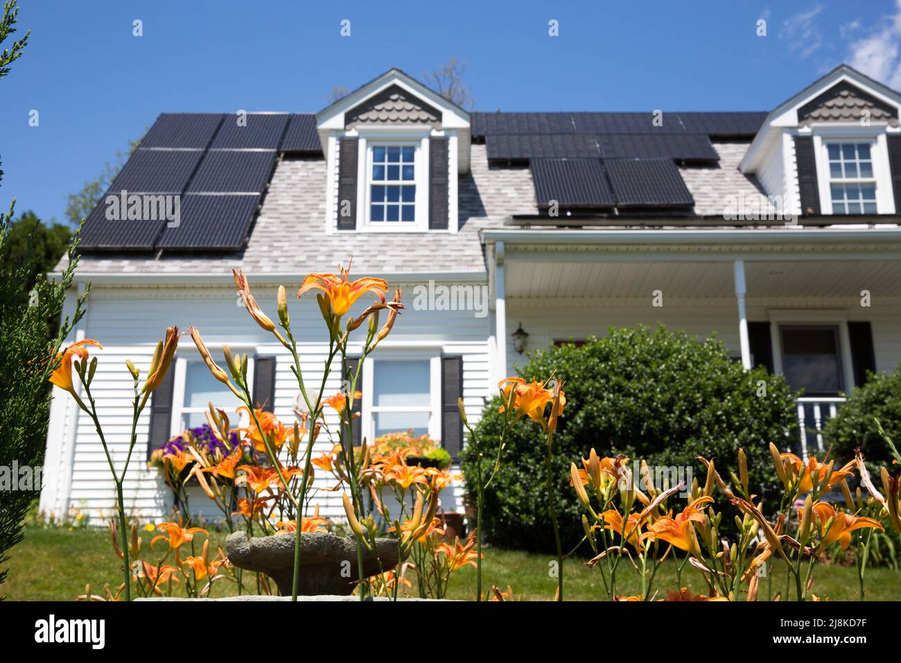 Solar panel installation on a nice cape cod house with sunny blue skies ...