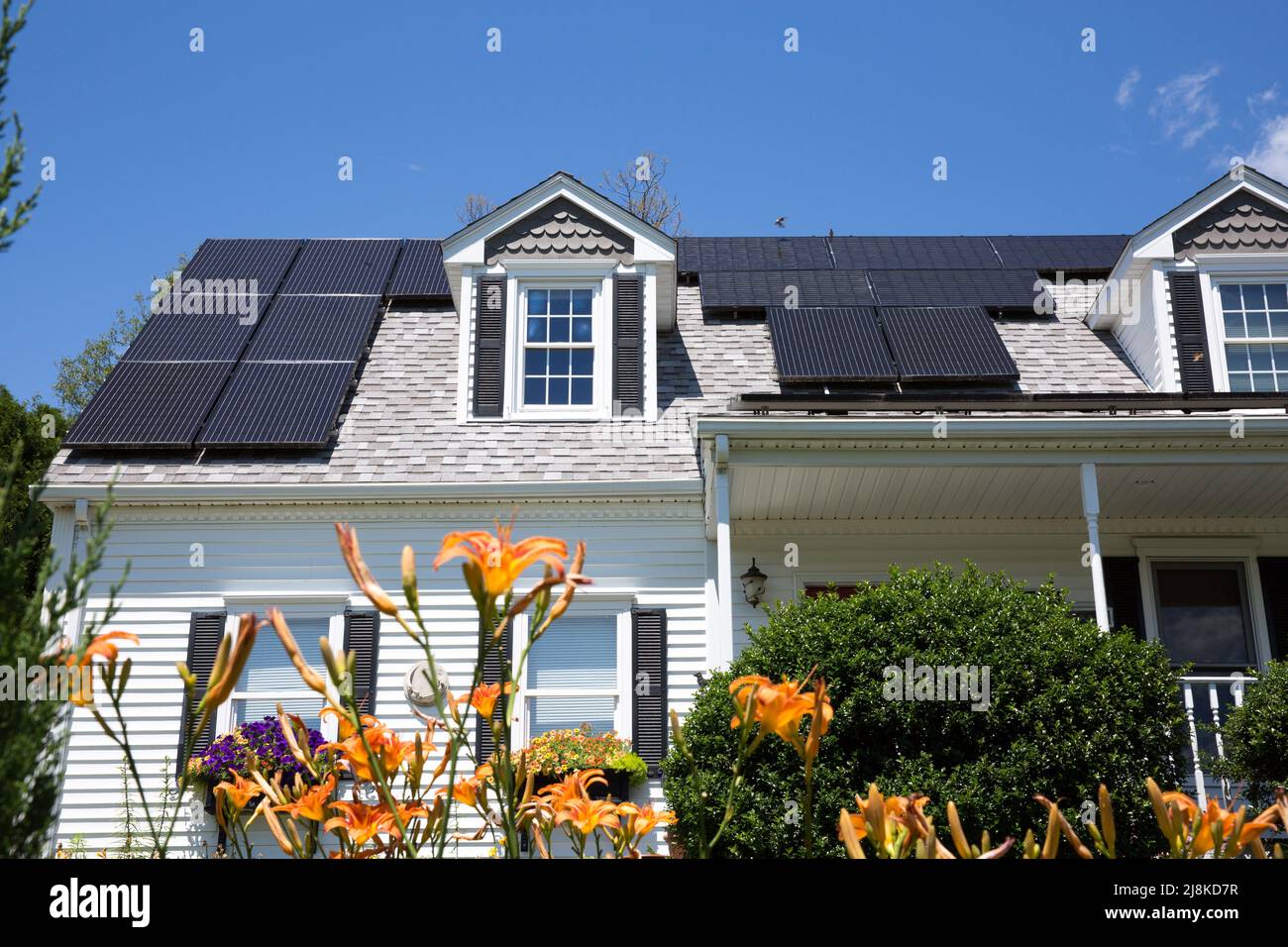 Solar panel installation on a nice cape cod house with sunny blue skies ...