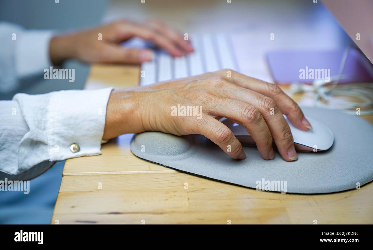 Woman's fingers clicking on mouse, resting her wrist on wrist rest ...