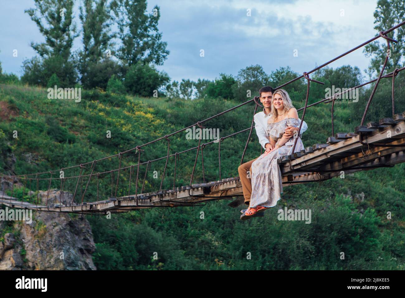 Beautiful young romantic couple sitting and hugging on the suspension ...