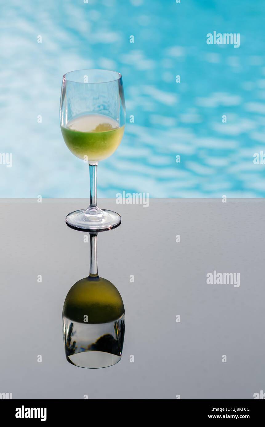 A glass of white wine puts on table at swimming pool for Holiday and ...