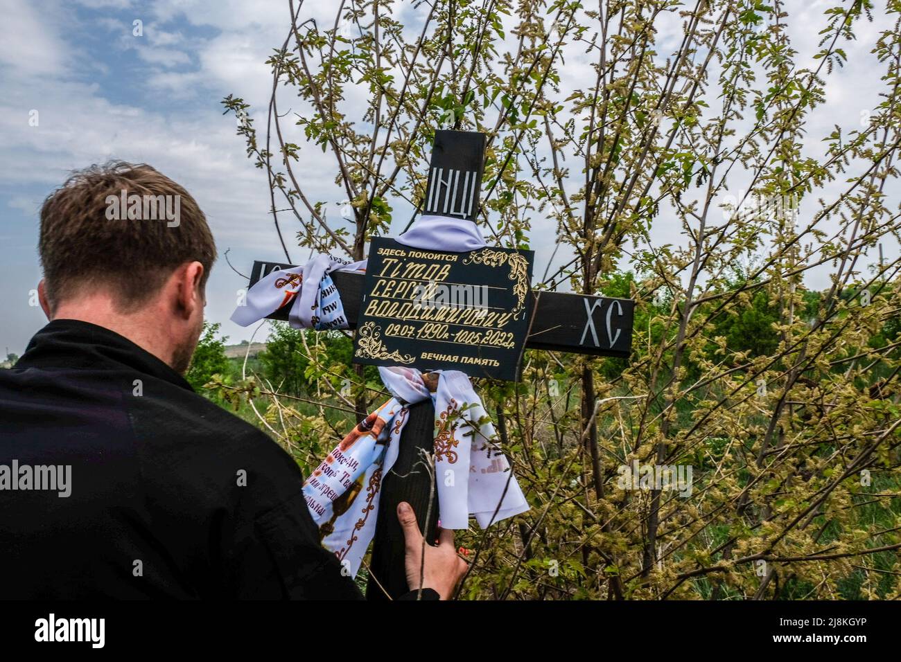 A funeral parlor worker prepares the cross to put on the grave of Sergey Titov, sergeant of the ...