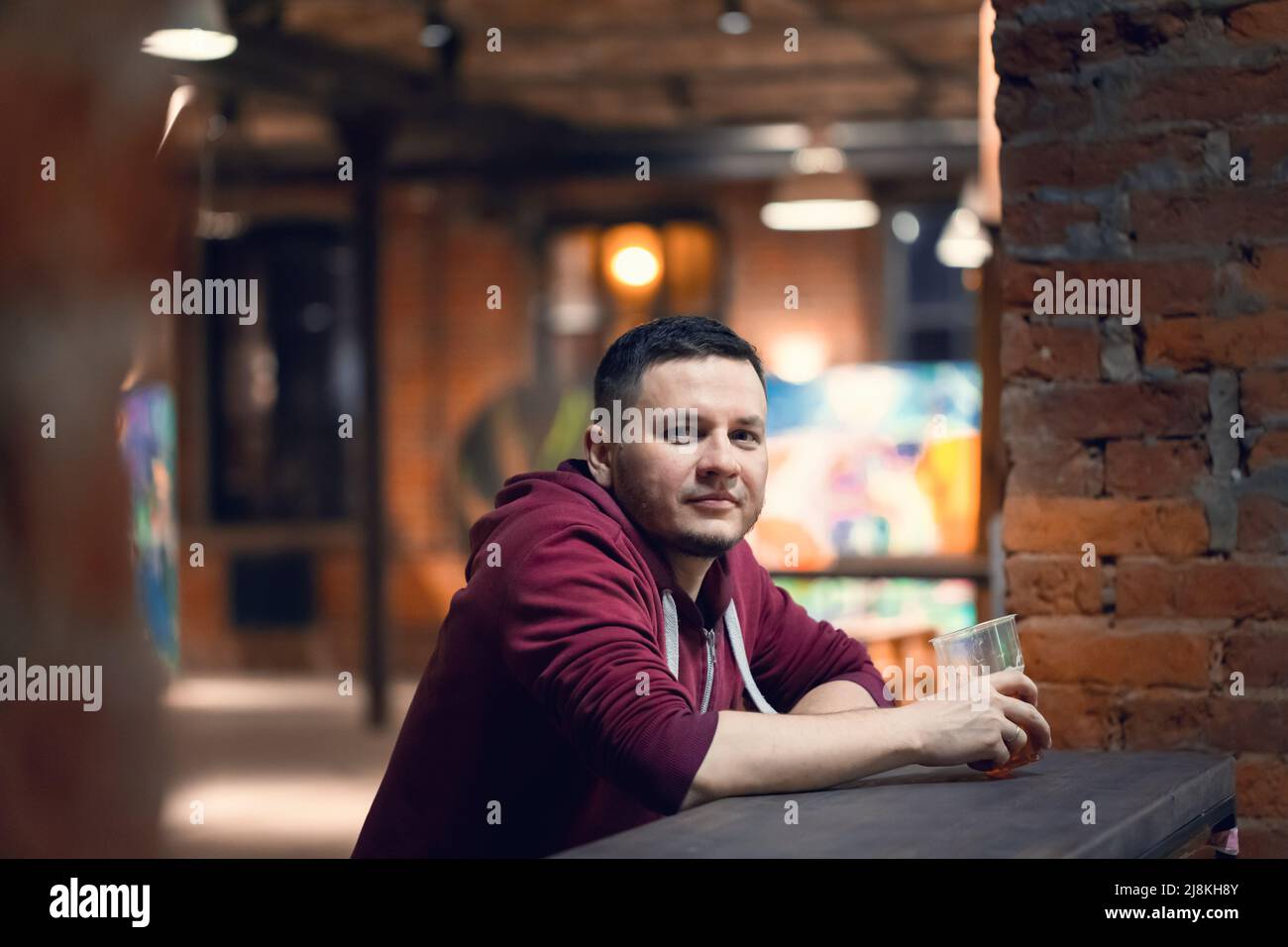Portrait of a man drinking beer in a loft style bar. Front view Stock ...