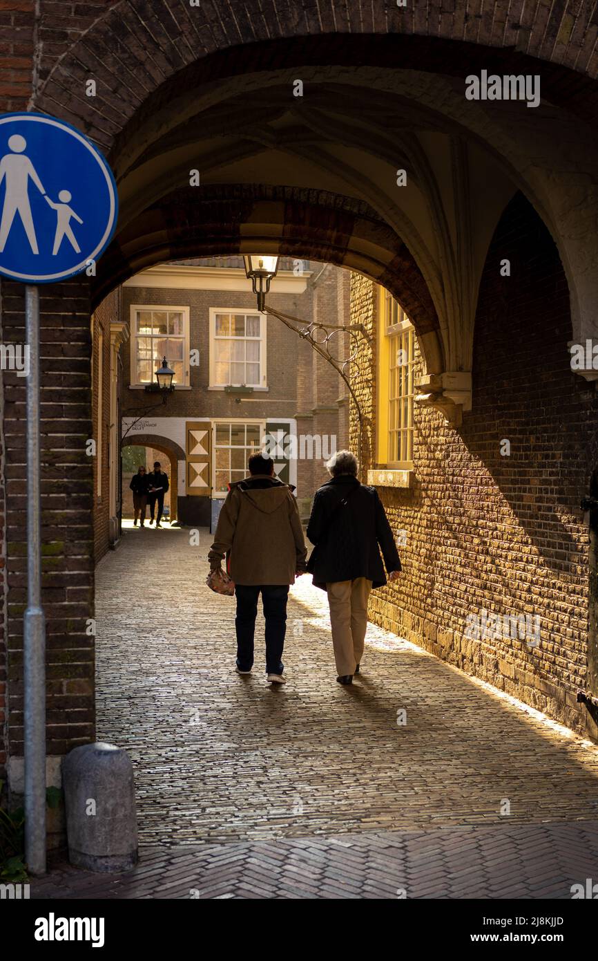 People passing through a back alley at sunset in Delft Netherlands ...