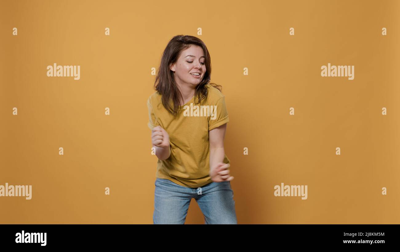 Positive woman full on energy dancing alone in studio feeling confident ...