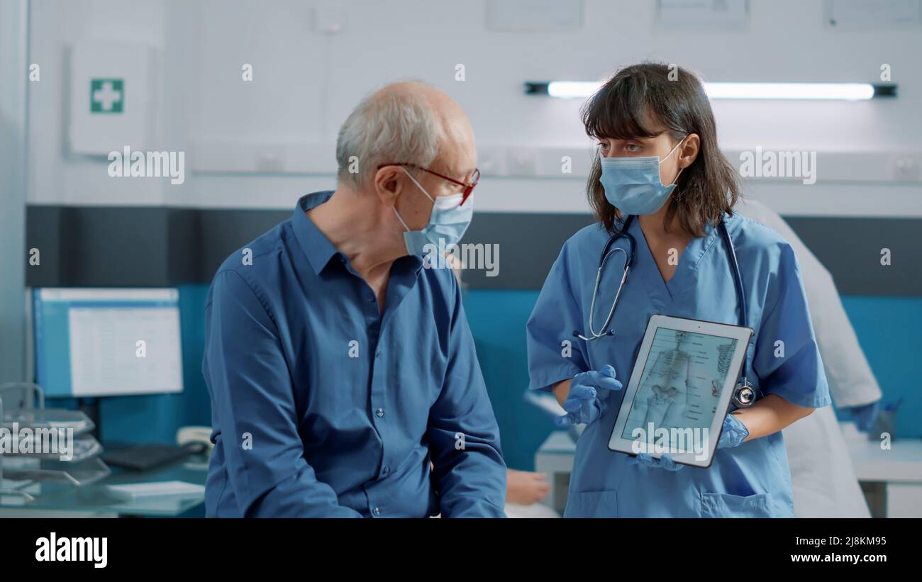 Female specialist explaining human skeleton illustration on tablet to ...
