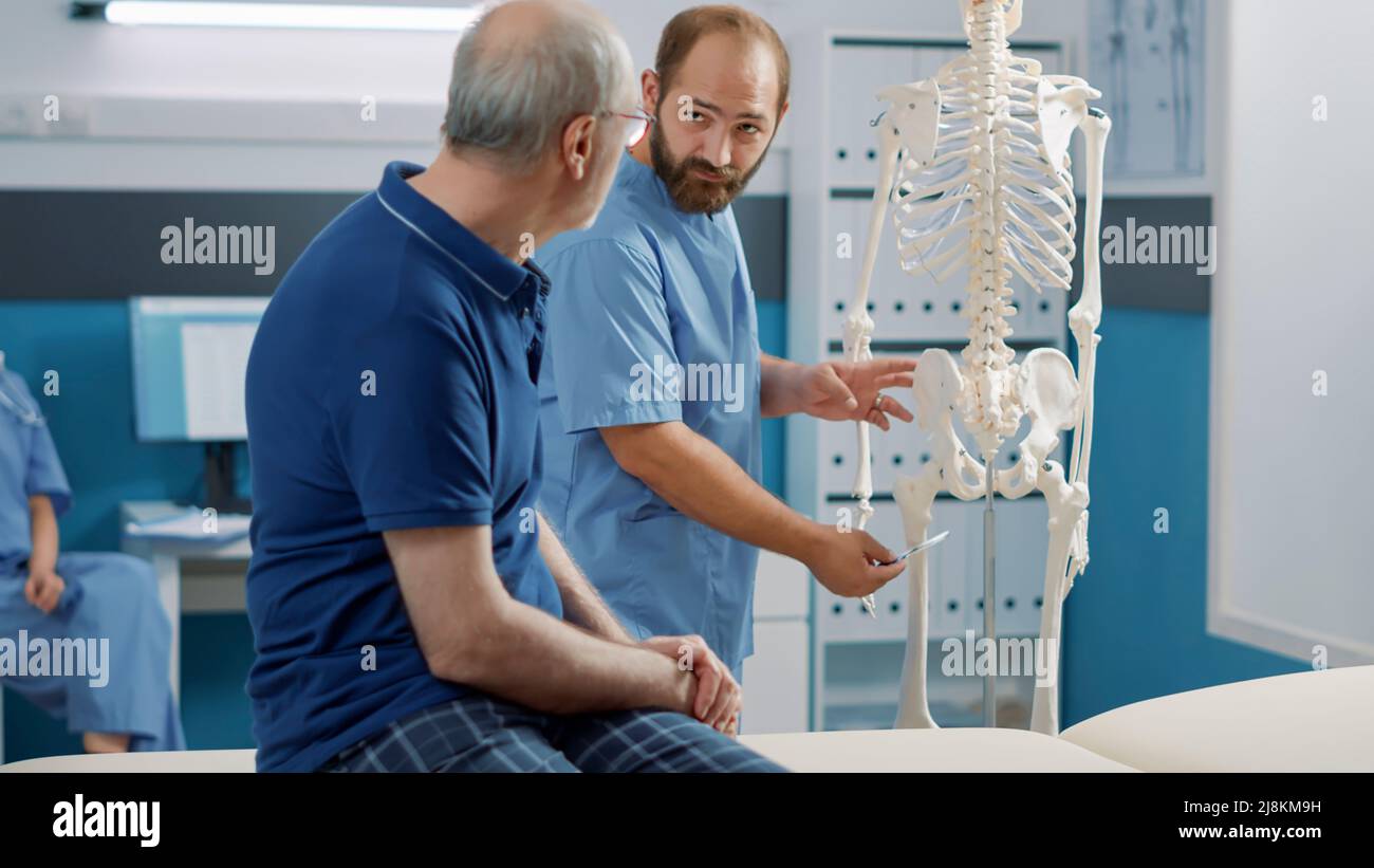 Osteopathy specialist explaining spinal cord system on human skeleton ...