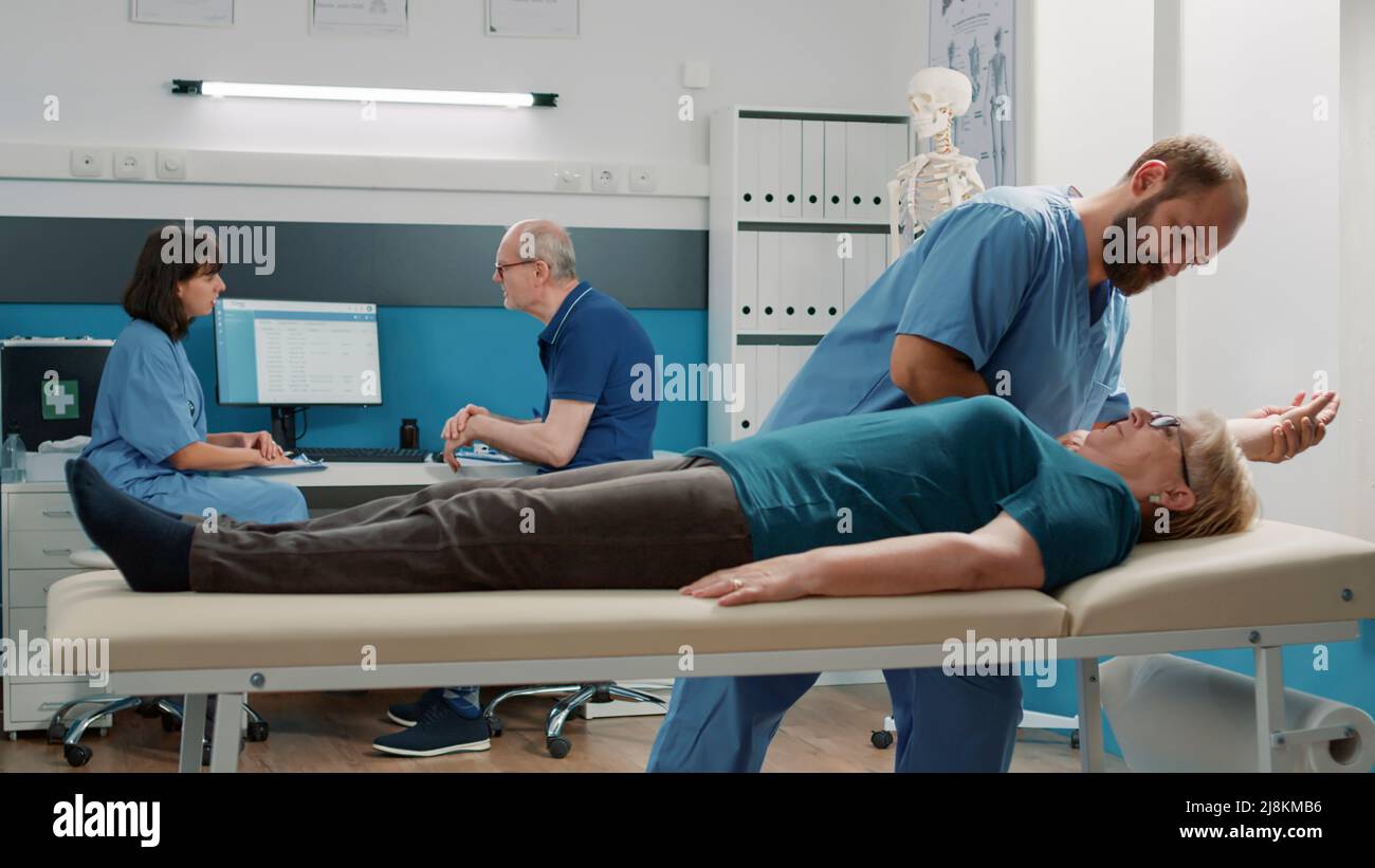 Physical recovery therapist raising arms to help senior woman with ...