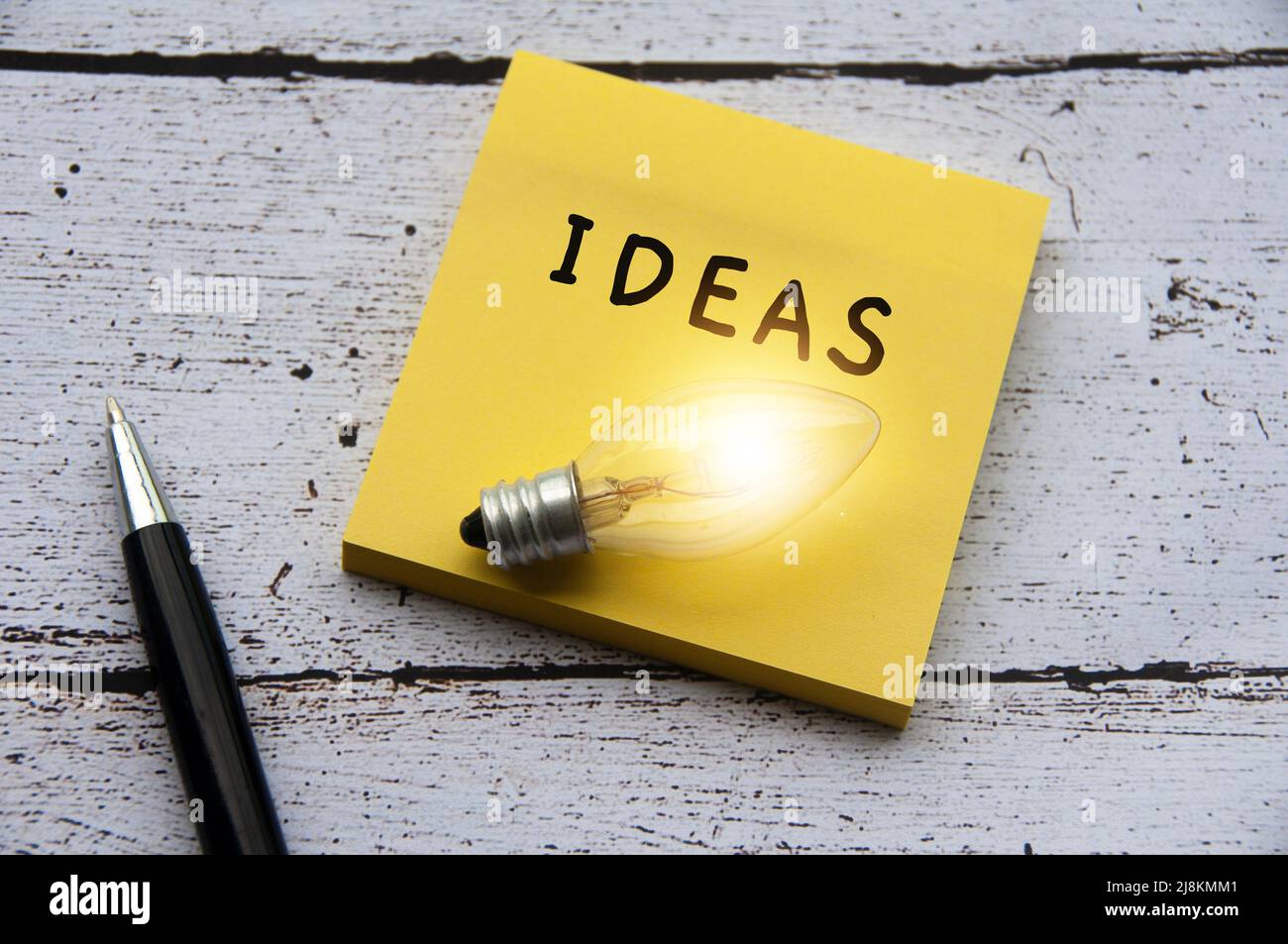 Ideas text with light bulb on notepad. Wooden desk and pen background ...