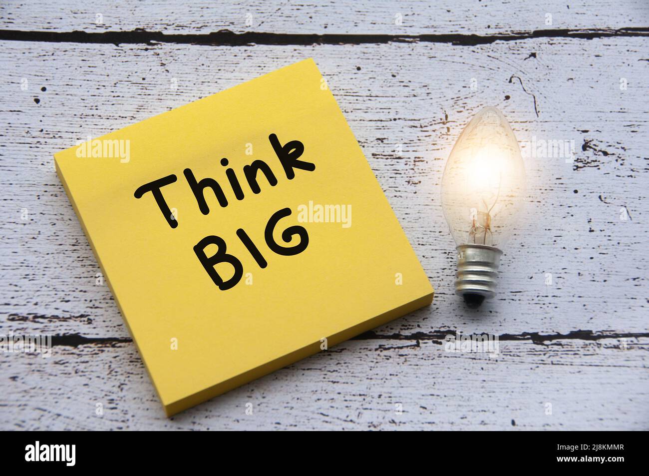 Think Big Text and Light Bulb on Paper Note. With wooden desk ...