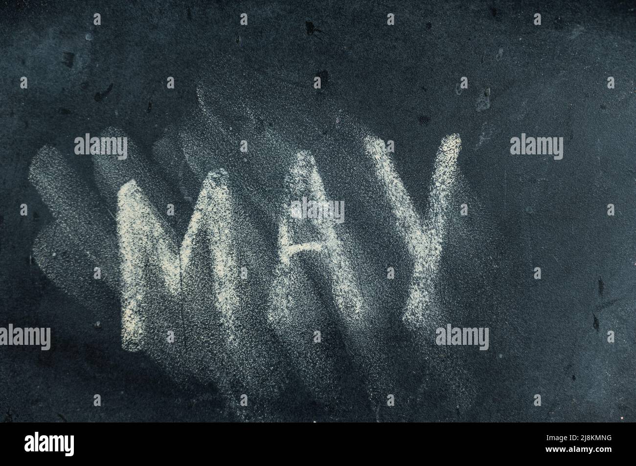 Semi-erased word MAY on black chalkboard. Handwritten word. Fuzzy ...