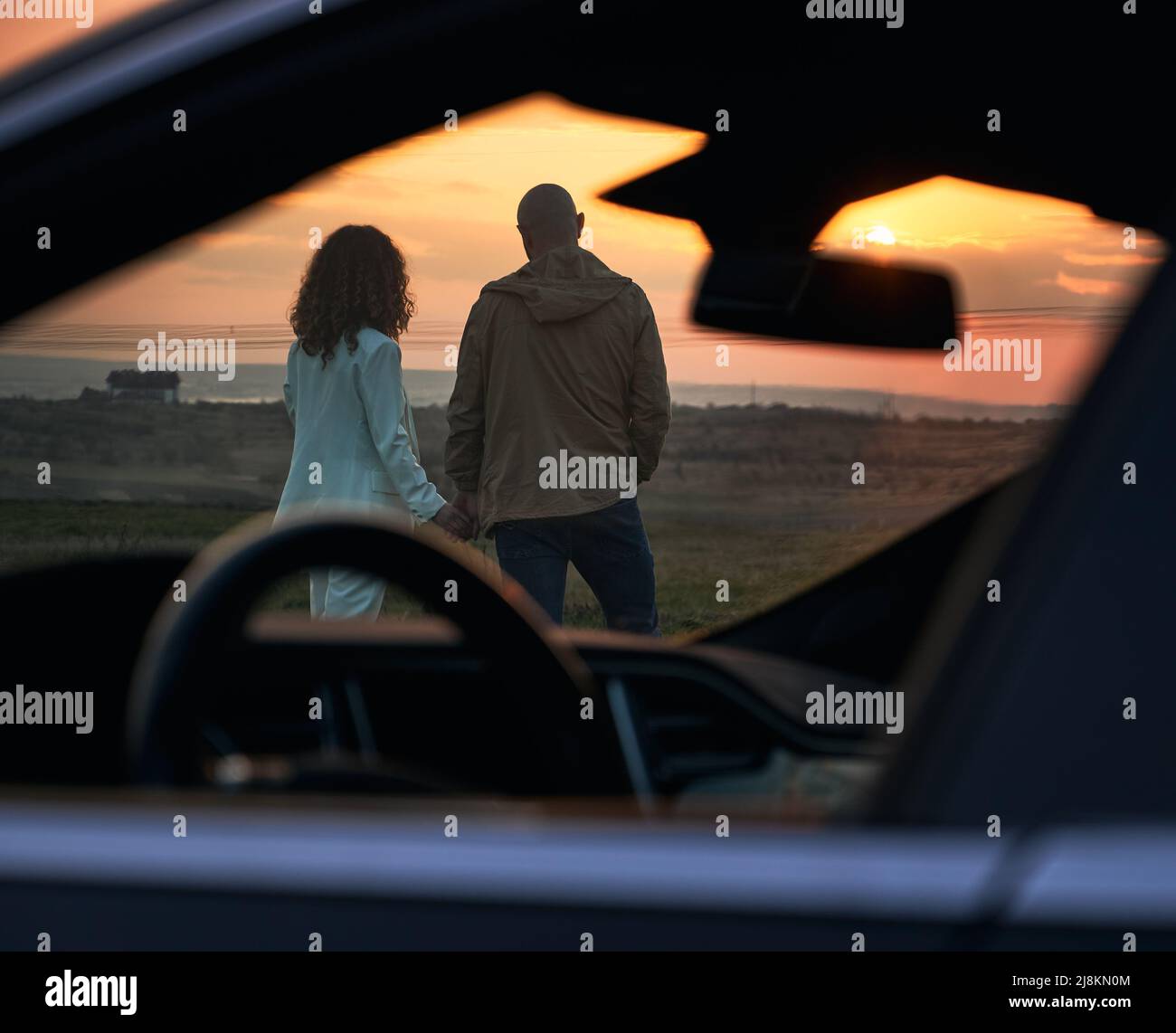 View through open side and front car window of couple in love. Back ...