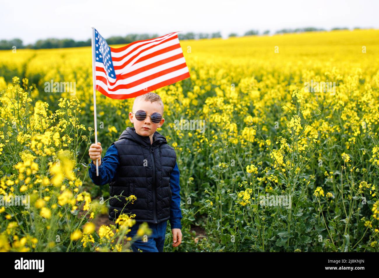 Closeup of a young patriotic boy stands among field. Boy standing with ...