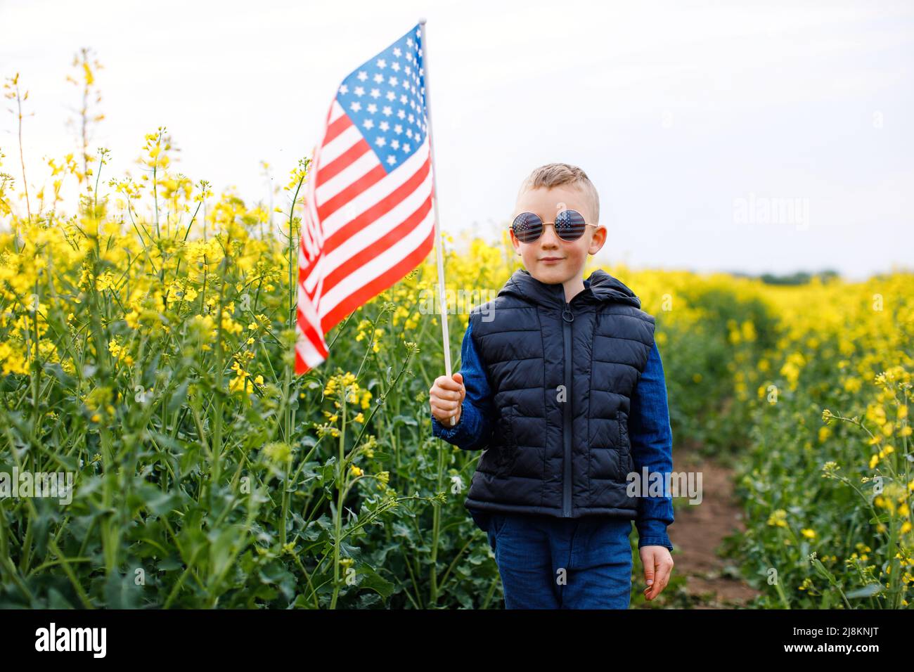 Closeup of a young patriotic boy stands among field. Boy standing with ...