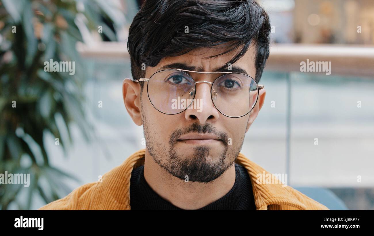 Close-up serious dissatisfied young arab guy student standing indoors ...