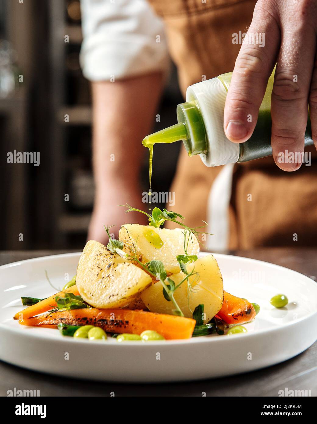 Chef pouring gourmet healthy dish with green sauce Stock Photo - Alamy