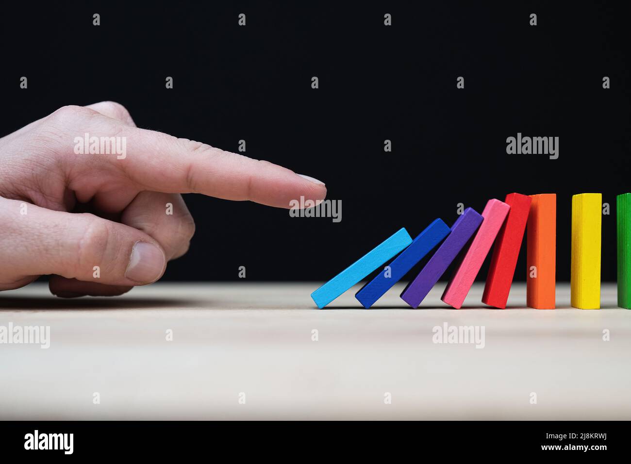 Conceptual photo of a hand starting a chain reaction with colored ...