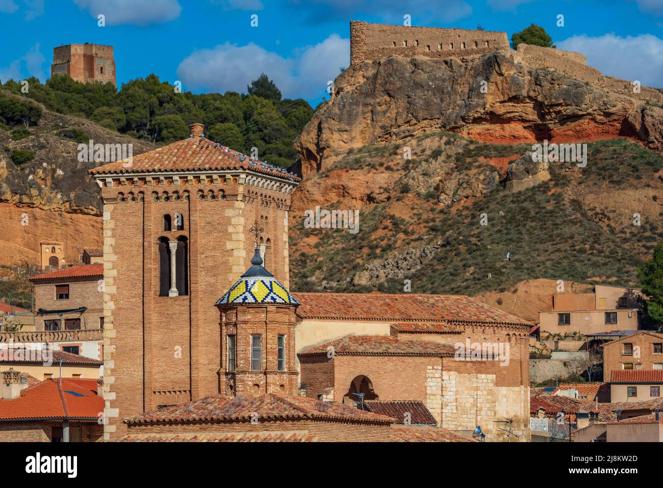 Ancient tower with colorful tile roof and castle in the background ...