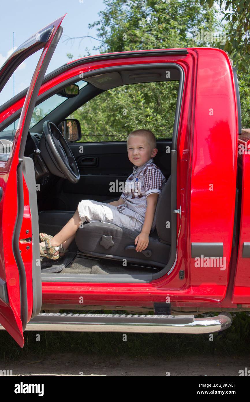 Little boy driver of red car sits on a chair Stock Photo - Alamy