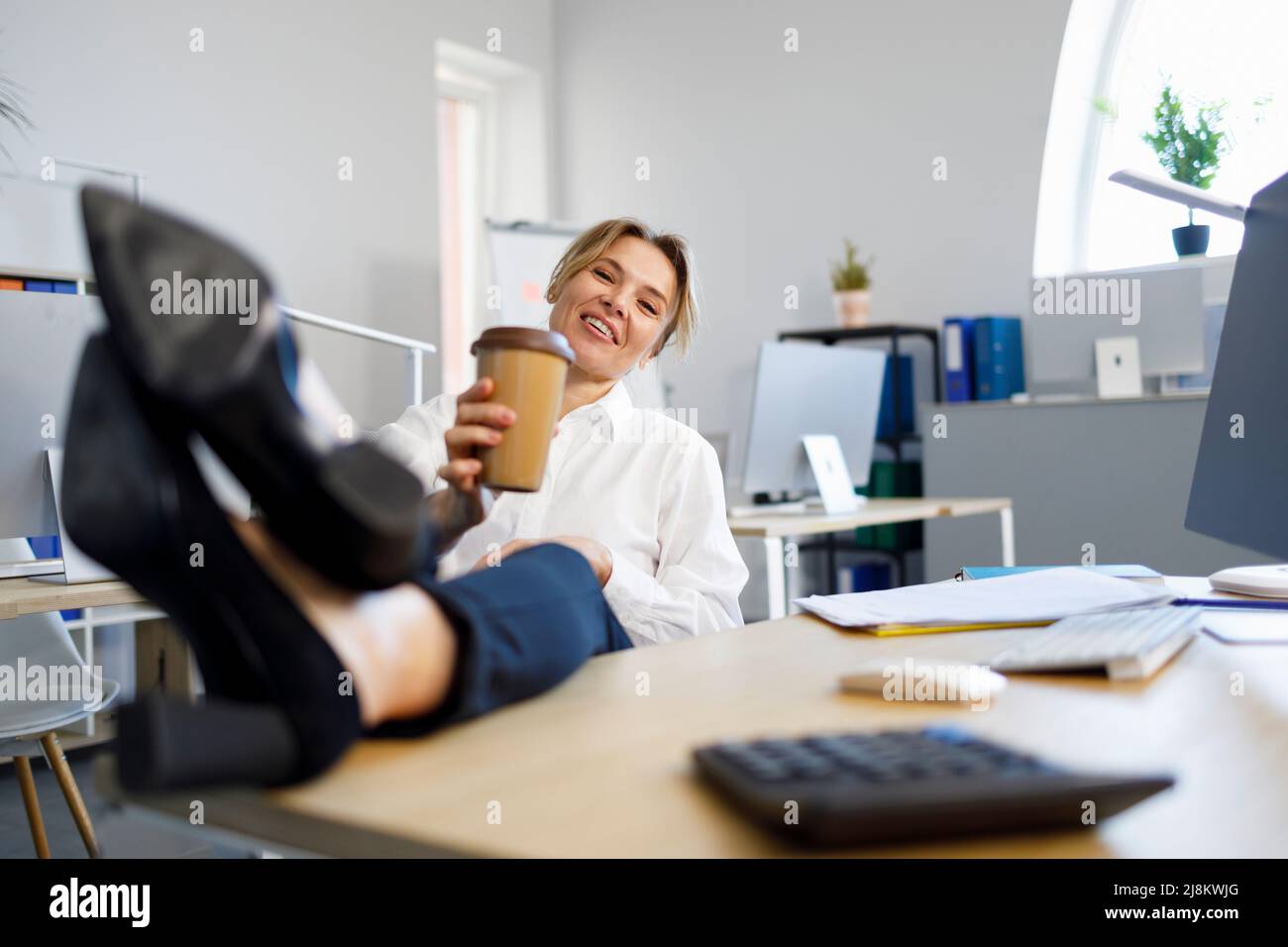 Business woman relaxing during coffee break putting legs on the desk ...