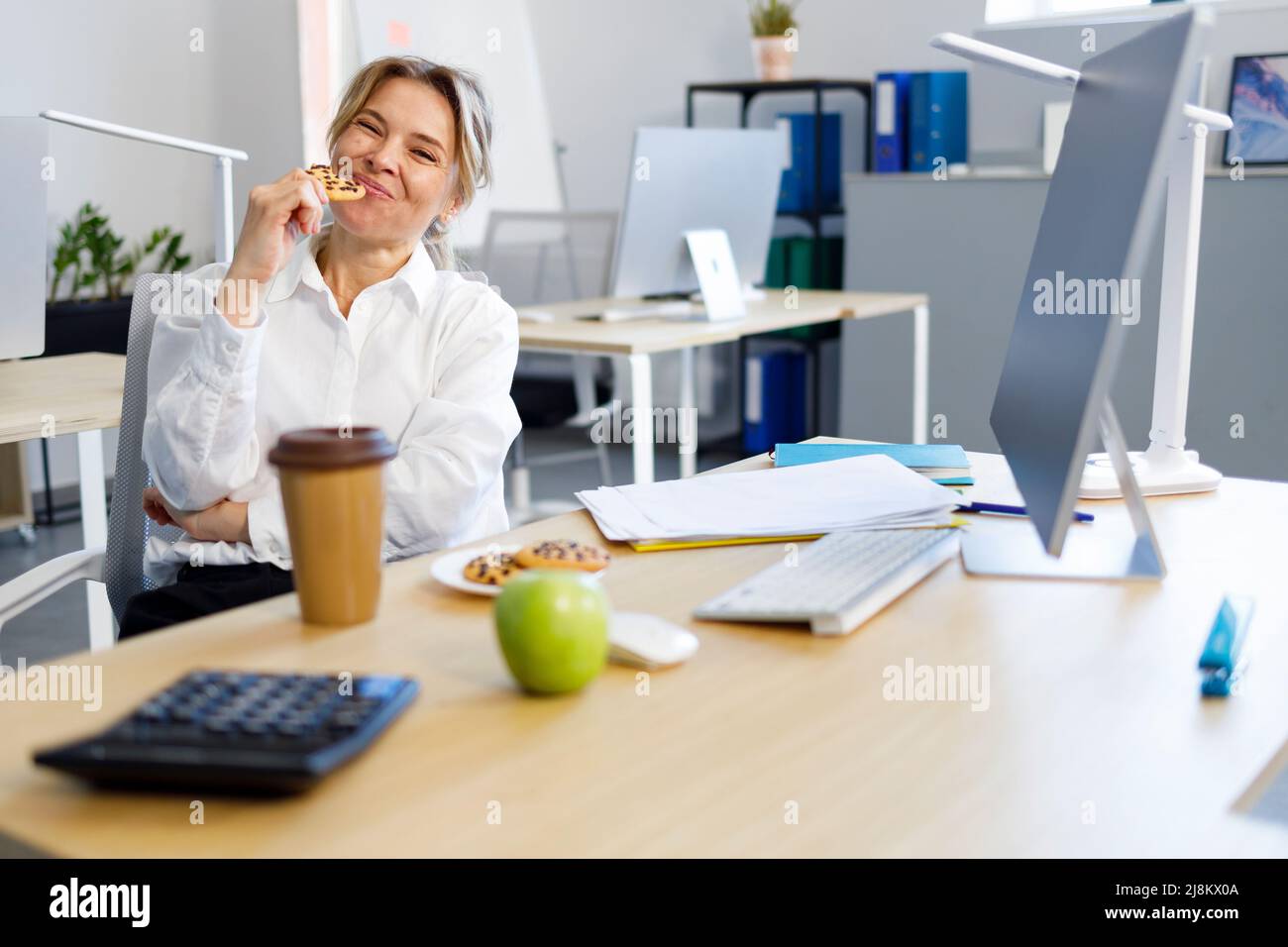 Business woman eating cookies at work Stock Photo - Alamy