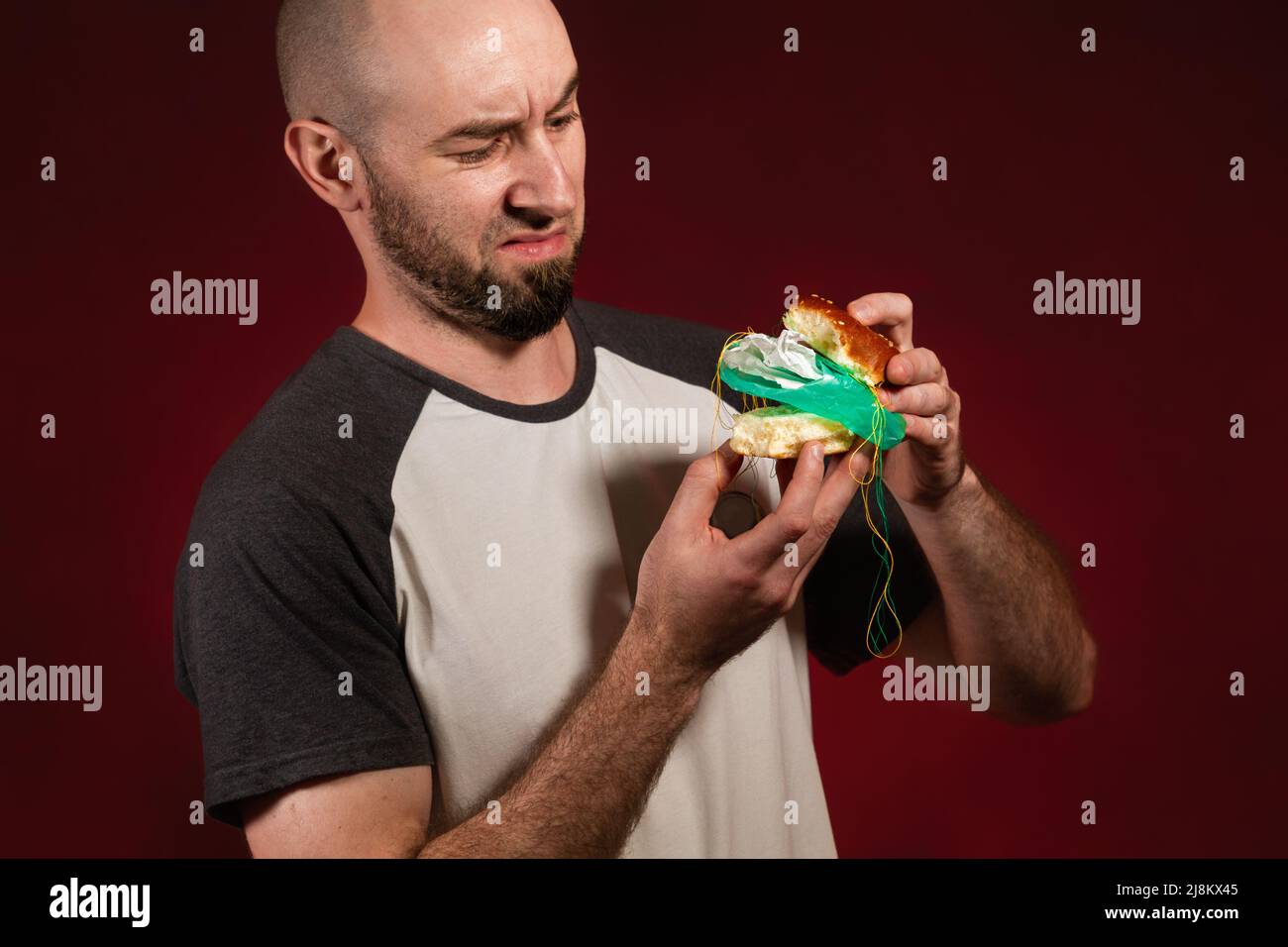 The concept of fast food and ecology. A bald man with a beard looks ...