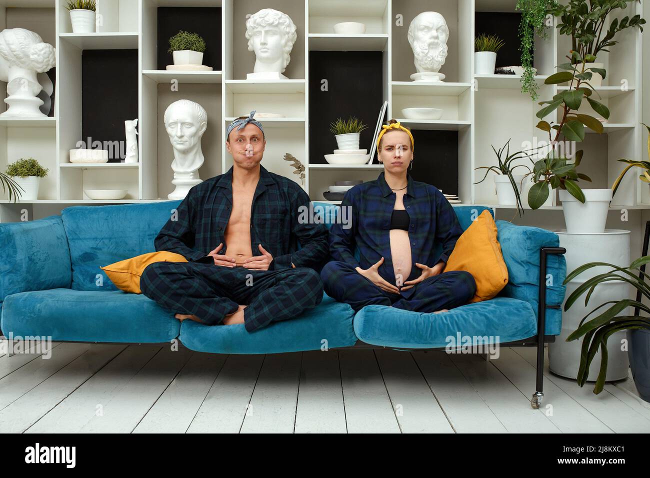 A pregnant man and woman are meditating in a lotus position on the ...