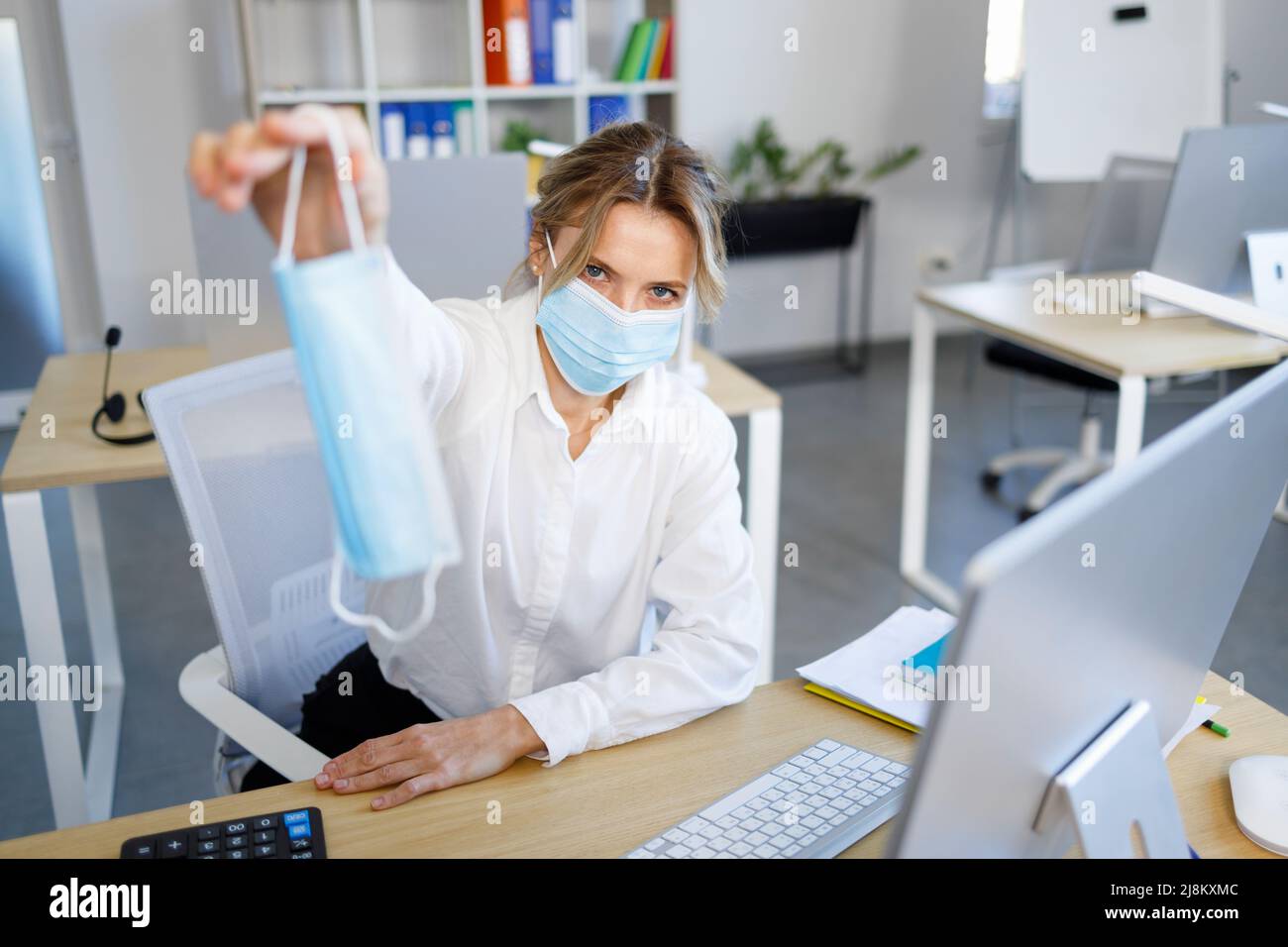 Strict female office worker in a mask shows a medical mask Stock Photo ...