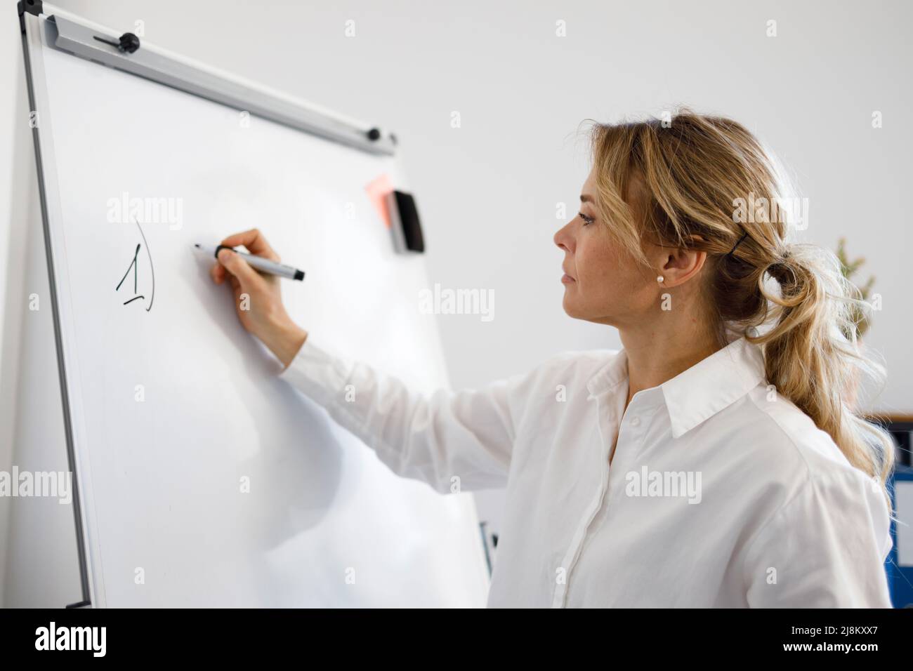 Business woman or teacher writing on flipchart Stock Photo - Alamy