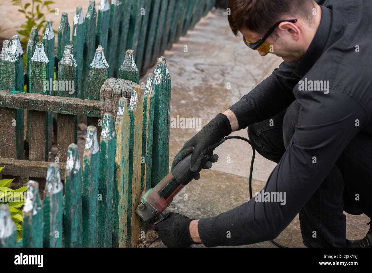 Sanding and preparing a wooden fence for painting. The master is ...