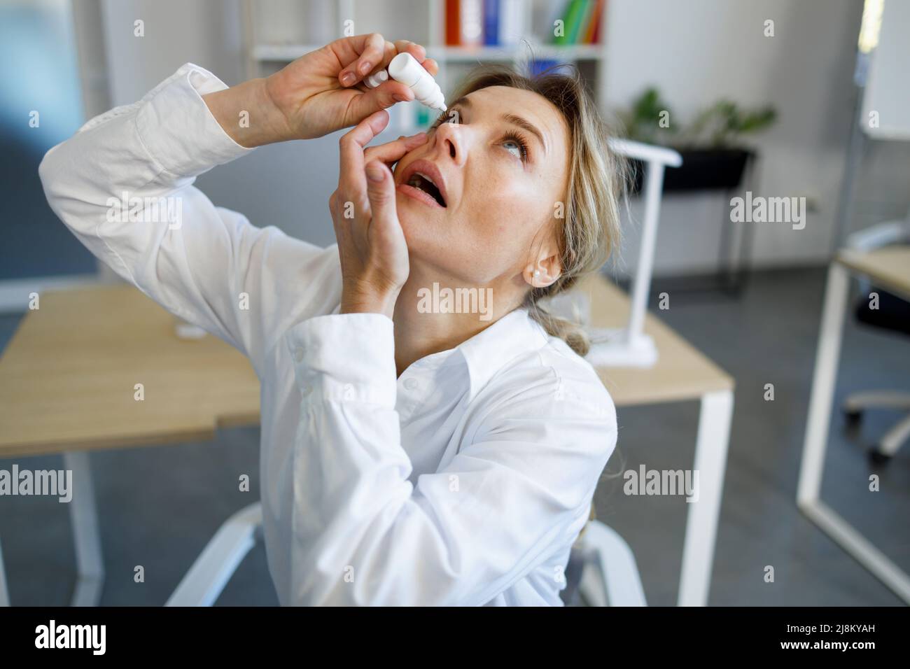 Business woman using eye drops Stock Photo - Alamy