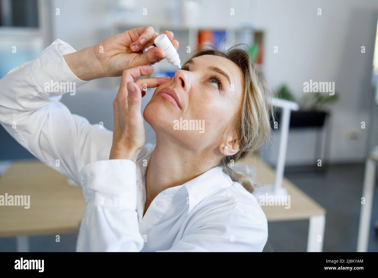 Business woman office worker dripping eye drops Stock Photo - Alamy