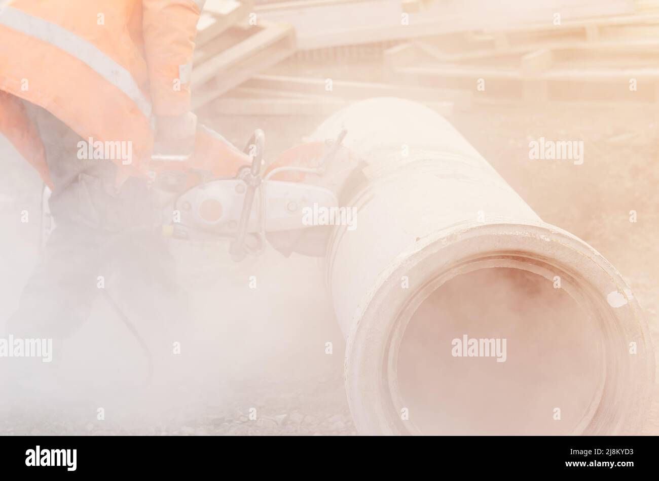 A worker at the construction site cutting a concrete drainage pipe with ...