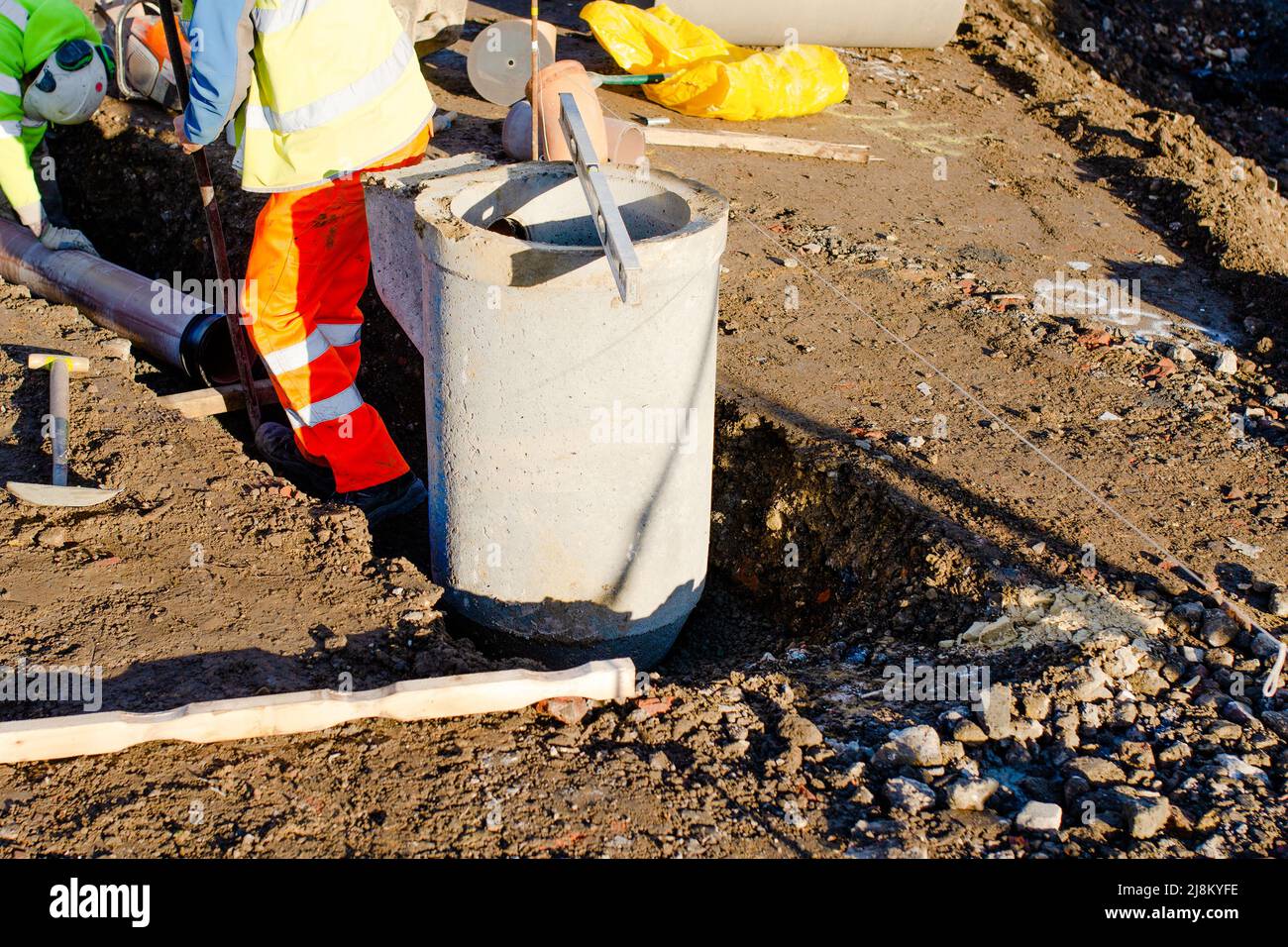 Groundworkers installing road gully during new road construction Stock ...