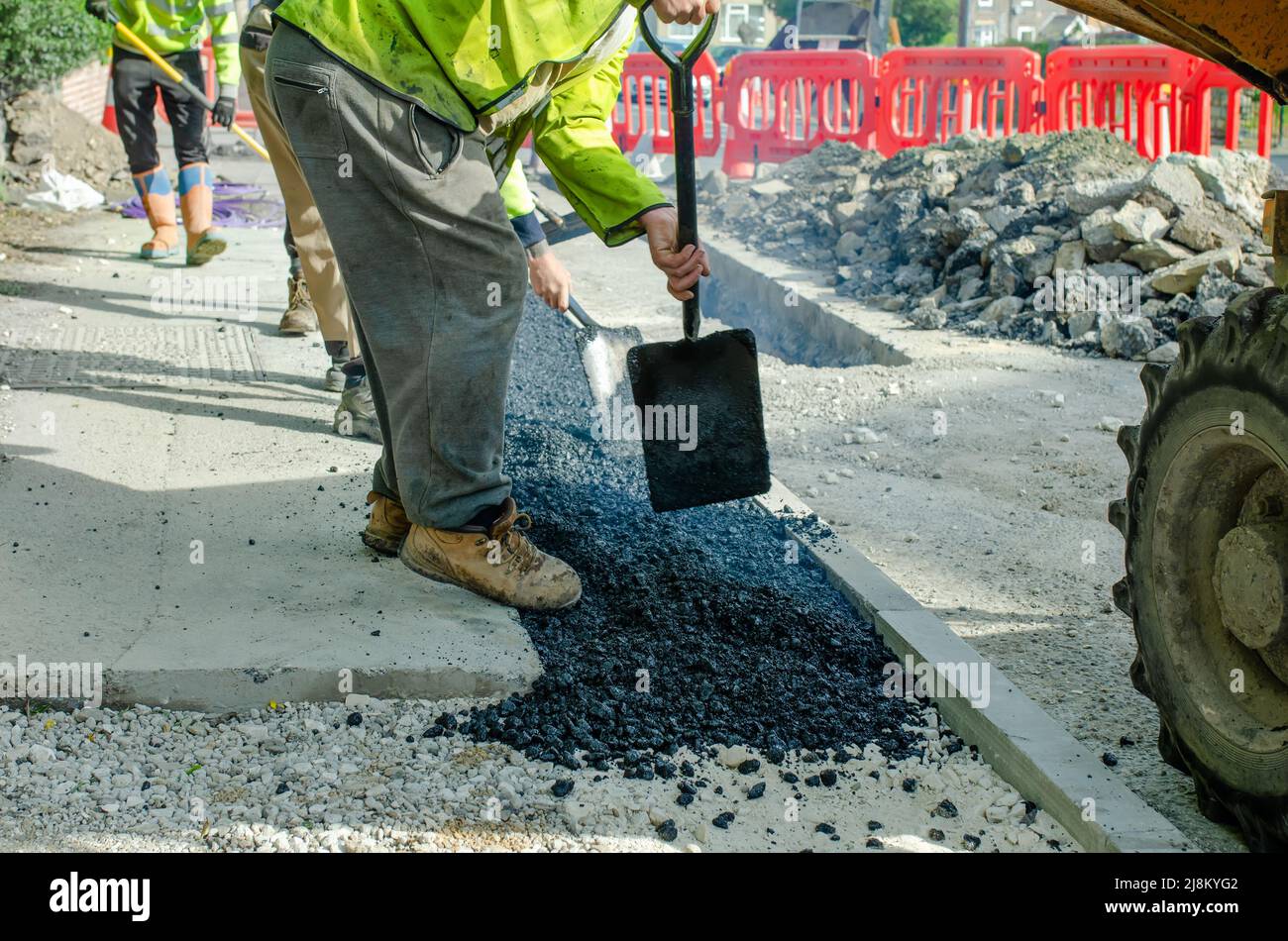 Construction workers placing hot tarmac after installation of new ...